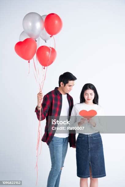 아름 다운 젊은 커플 집에서 포옹 키스 그리고 백그라운드에 심장의 모양에서 공기 풍선을 손에 선물 상자와 함께 성 발렌타인의 날을 축 하 하면서 함께 시간을 보내고 즐기는