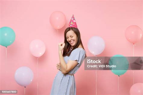 생일 모자 블루 드레스 하 고 우승자 제스처 말 네 화려한 공기 Baloons와 분홍색 배경에 닫힌된 눈을 가진 아름 다운 행복