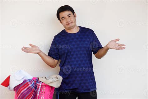 Asian Man Stands Beside Basket Of Clothes Put Hands On Hips Feeling