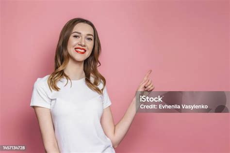 흰색 티셔츠를 입은 소녀는 미소를 지으며 복사 공간을 손가락으로 가리킨다 30 34세에 대한 스톡 사진 및 기타 이미지 30 34세 가리키기 갈색 머리 Istock