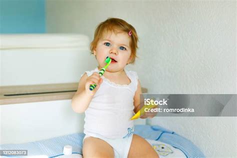 칫솔을 들고 첫 번째 치아를 닦는 어린 아기 소녀 우유 치아를 청소하는 법을 배우는 유아 예방 위생 및 의료 개념 욕실에서