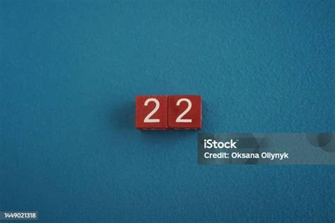 파란색 배경 클로즈업 상위 뷰에 숫자 22가 있는 나무 Viva 마젠타 큐브 날짜 또는 시간의 개념입니다 빨간색 큐브 벨벳 배경에 흰색 숫자 22 텍스트 또는 이벤트를 위한