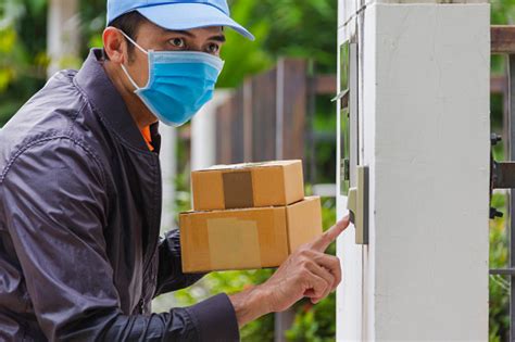 배달 남자는 위생 마스크와 파란색 모자를 착용 종과 고객의 집 앞에서 골판지 상자를 들고 배달부에 대한 스톡 사진 및 기타 이미지 배달부 벨 소포 Istock