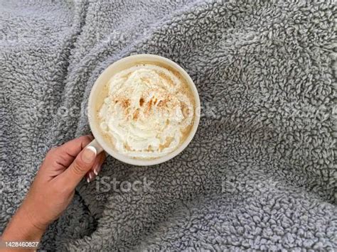 호박 향신료 라떼 핫 가을 커피와 에스프레소 음료를 휘핑 크림과 향신료가 든 컵에 들고 복사 공간이있는 아늑하고 따뜻한 부드러운 회색 담요 위에 손을 얹은 손 펌킨 스파이스