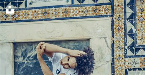 흰 셔츠를 입은 여자가 월wal 근처의 베이지색 금속 튜브 포스트에 균형을 잡고 있다 사진 Unsplash의 무료 튀니지 이미지