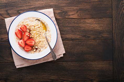 오트밀 오래된 나무 어두운 테이블 배경에 딸기 아몬드 및 우유가있는 오트밀 죽 그릇 평면 누워 스타일의 상단보기 천연 성분