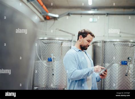 The Winemaker Standing In The Wine Cellar Monitoring The Fermentation