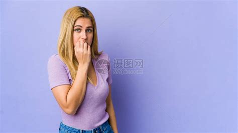 年轻金发女郎被紫色背景的咬指甲隔离神经紧张高清图片下载 正版图片504370048 摄图网