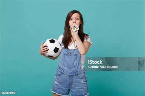 깜짝 놀라게 젊은 여자 축구 팬 응원 축구 공 스튜디오에서 파란색 청록색 배경에 고립 된 파이프와 함께 좋아하는 팀 지원 사람들의 감정 스포츠 가족 레저 개념입니다 복사