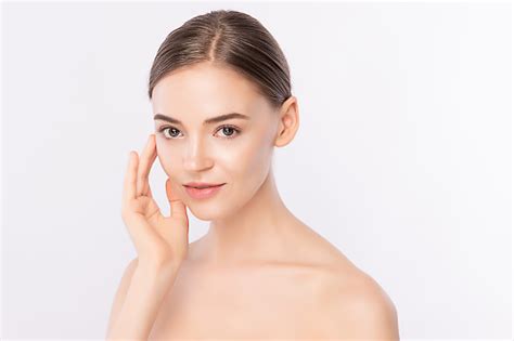 하얀 배경 뷰티 코스메틱 얼굴 트리트먼트 컨셉으로 고립된 신선한 건강한 피부로 깨끗한 얼굴을 만지는 아름다운 젊은 여성 건강