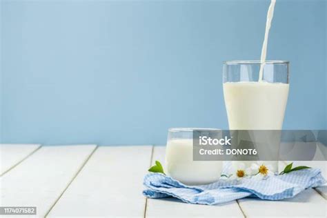 파란색 배경에 흰색 나무 테이블에 우유 한 잔을 붓고 맛있고 영양가 있고 건강한 유제품 건강한 식생활에 대한 스톡 사진 및 기타 이미지 건강한 식생활 꽃 식물 따르기