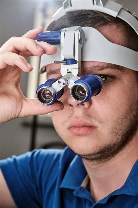 Dentist With Binocular Magnifying Glasses Working In Dental Clinic