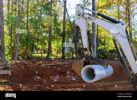 Un Travailleur Du Tracteur Installe Des Tuyaux Dévacuation En Béton En