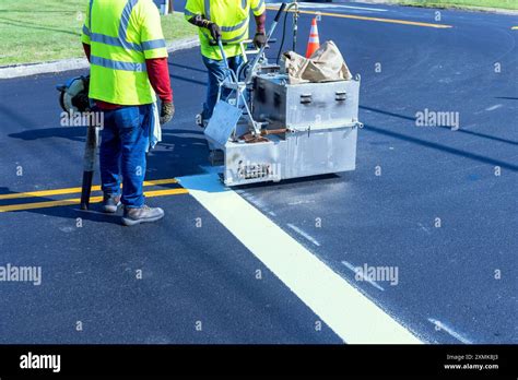 using an airbrush machine workers apply marking signs after asphalt