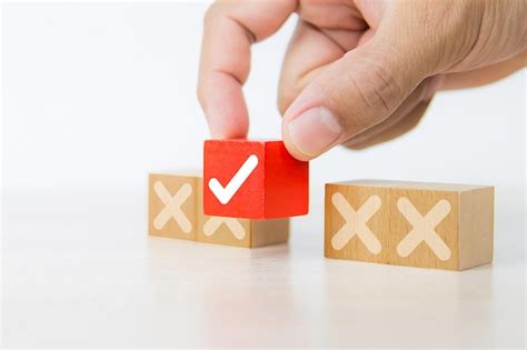 Premium Photo Hand Choose Check Mark On Cube Wooden Toy Block With Cross Symbol