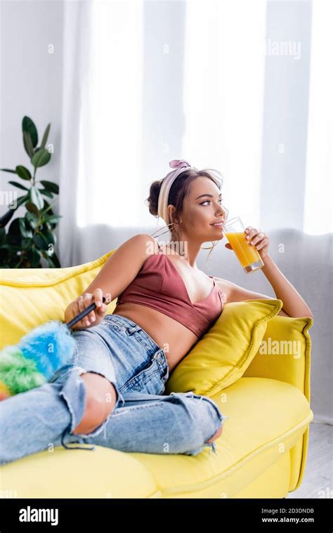Selective Focus Of Housewife Drinking Orange Juice While Holding Dust