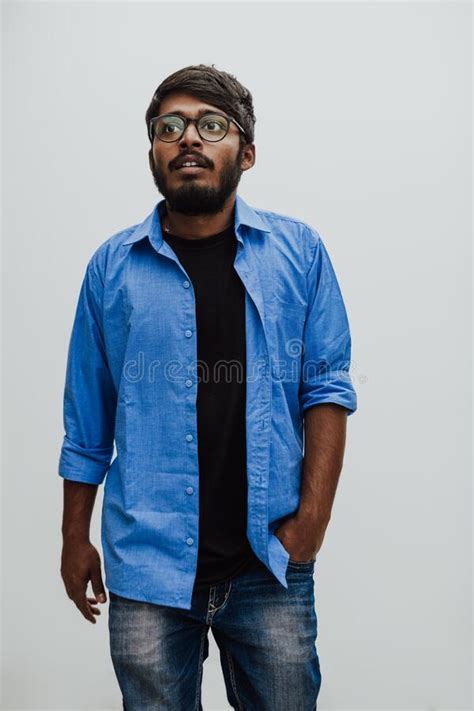 Indian Smiling Young Man With Blue Shirt And Glasses Posing On Gray