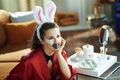 Female With Bunny Ears Making Cosmetic Lip Mask And Eye Mask Stock