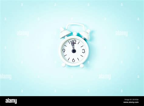 White Vintage Style Alarm Clock Showing Five Minutes Left Untill Midnight Over Blue Background