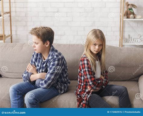 Brother And Sister Not Talking After Quarrel Sitting On Couch Stock