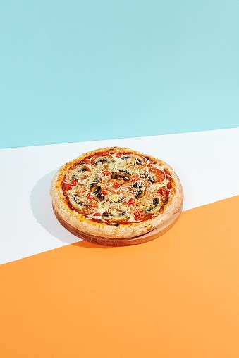 컬러 배경에 버섯과 치즈가 들어간 이탈리아 피자 버섯과 토마토를 곁들인 비건 피자는 파란색과 주황색에 최소한의 스타일로 제공됩니다 컬러 배경을 가진 미국 피자 배달 개념