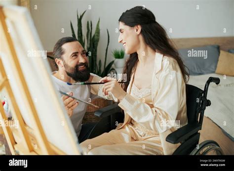 Appealing Woman With Mobility Disability Painting On Easel Next To Her