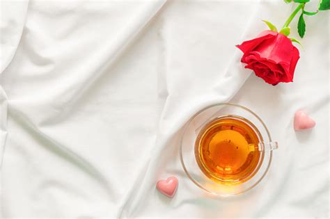 복사 공간이있는 흰색 침대에 빨간 장미와 하트 모양의 사탕이있는 차 한 잔의 꼭대기 전망 로맨틱 한 서프라이즈 컨셉 가정의 방에