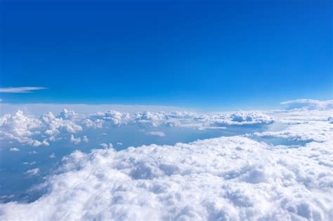 明るい太陽と青い空に美しい積雲ふわふわ白い雲。完璧な抽象的な空の背景、壁紙、レイアウト。飛行機の窓から雲の上の日の出 プレミアム写真