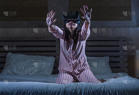 年轻快乐和兴奋的女孩玩虚拟现实vr眼镜耳机设备在床上有乐趣的3d体验视频游戏震惊的看和触摸数字幻觉