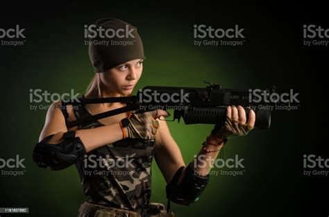 안개에 어두운 배경에 자신의 손에 총을 들고 포즈를 취하는 군사 바지 에어 소프트의 소녀 Airsoft Sport에 대한
