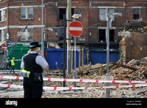 A Police Officer Looks At The Ruins Of A Burnt Down Furniture Store