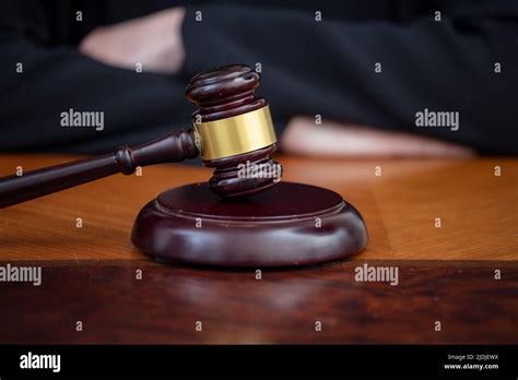 Judge gavel on wooden court desk, blur female crossed hands, close up view. Justice and law ...