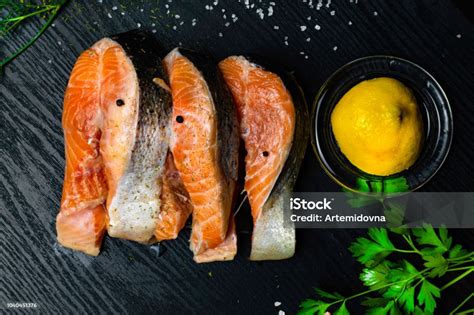 레드의 슬라이스 연어 송어에 검은 나무 배경과 텍스트 복사 공간에 레몬 파 슬 리 딜 핑크와 화이트 소금 Selery 그린