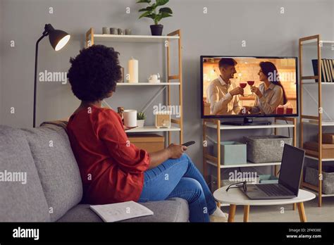 Young Woman Sitting On Couch At Home And Watching Romantic Soap Opera