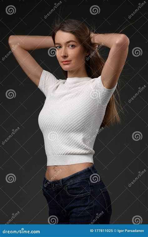 Beautiful Girl In A White T Shirt And Jeans On A Gray Background Stock