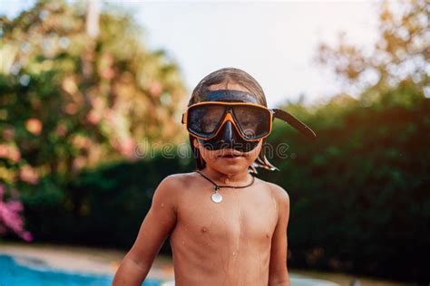 Niño Desnudo Posando En Cámara Alrededor De La Piscina Sosteniendo Sus Gafas Foto de archivo