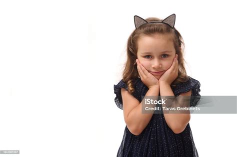 고양이 귀와 후프에 있는 작은 마녀 소녀 세련된 카니발 드레스를 입고 턱 아래 손바닥을 들고 카메라를 보고 흰색 배경에 교차 팔로 포즈를 취하고 공간을 복사하고 할로윈을