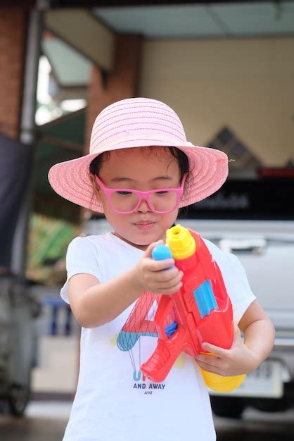 Premium Photo Cute Girl Holding Squirt Gun While Standing Outdoors