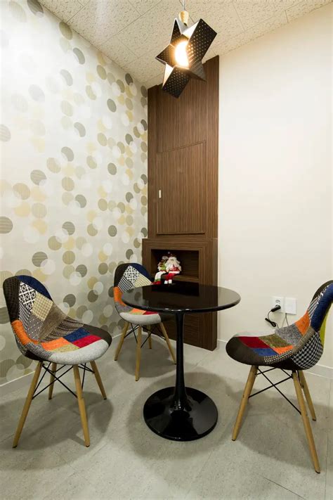 원형 패턴 벽과 별 모양 팬던트 조명 블랙 원형 테이블에 다채로운 패턴의 의자가 돋보이는 뷰티 아카데미 실내 가구 사진