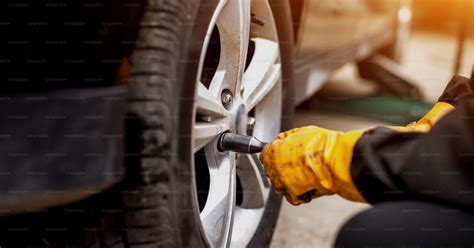 주황색 장갑을 낀 숙련 된 열심히 일하는 정비사가 전기 렌치를 사용하여 자동차 바퀴의 나사를 조이고 있습니다 사진 Unsplash의 바퀴 이미지