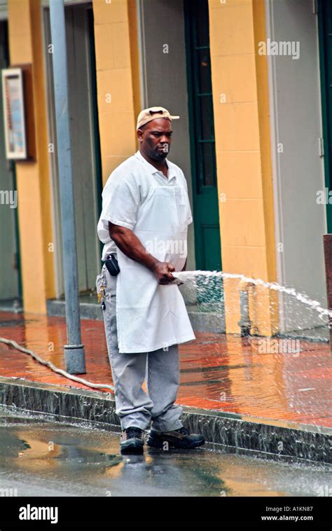 Man With Garden Hose Appearing To Be Peeing In Street Stock Photo