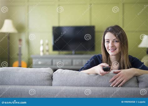 Beautiful Woman Watching TV Sitting On Couch At Home Stock Photo
