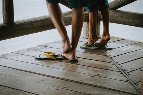 Premium Photo Low Section Of People Wearing Flip Flops On Wooden Floor