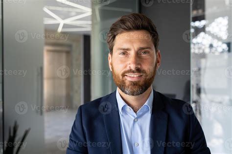 Confident Businessman In A Suit Smiling In A Modern Office Setting