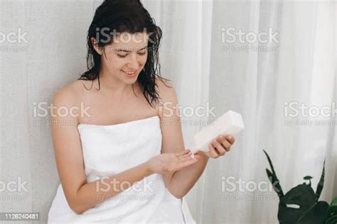 피부와 바디 케어입니다 흰 수건 적용 보습에 여자 크림 녹색 식물에 가정 욕실에 행복 한 영 핸드 로션과 플라스틱 병을 들고