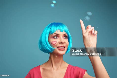 파란 가발과 비눗방울에 밝은 화장을 한 아름 다운 젊은 여자 패션 모델 소녀 와 창조적 인 색상 메이크업 여성 인형 개념입니다