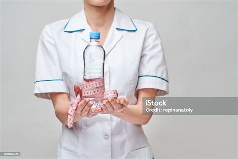 젊은 백인 여성 건강 관리 전문가의 초상화물 병 들고 물 과 측정 테이프 빛 회색 배경 위에 서 30 34세에 대한 스톡 사진
