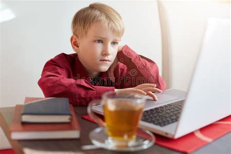 Ernster Blonder Kleiner Junge Im Roten Hemd Das Vor Dem Offenen Laptop