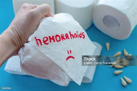 파란색 배경에 화장지와 항문 촛불 의 롤 옆에 단어 치질와 남자의 손에 화장지롤 가정 생활에 대한 스톡 사진 및 기타 이미지 가정 생활 건강관리와 의술 깨끗한