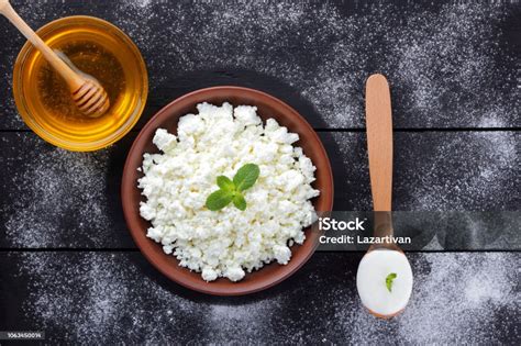 점토 그릇에 나무 보드에 허니 코 티 지 치즈 나무로 되는 숟가락에 사 우 어 크림입니다 낙농 제품과 어두운 배경에 꿀입니다